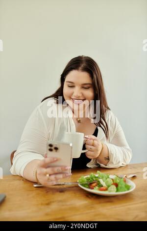 A vibrant plus size woman sips coffee while working on her laptop ...
