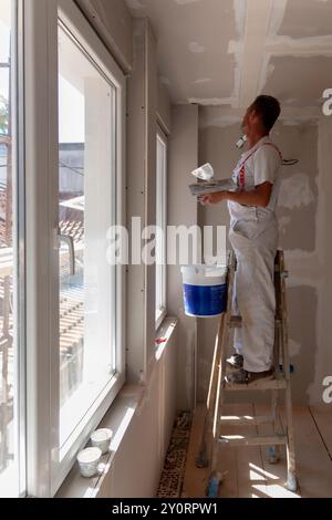 Repairman inside a house under construction. Repairman with blueprints ...