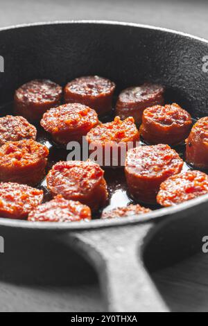 Spanish chorizo frying in olive oil in a cast iron frying pan. Edited ...