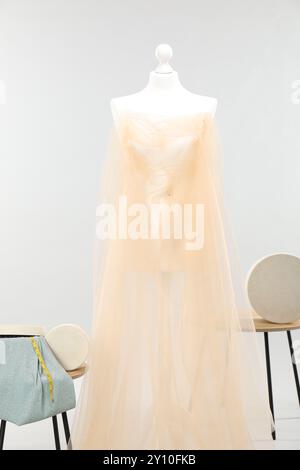 Mannequin with fabric and boxes on side table against light grey ...
