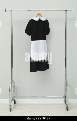 Maid's uniform on clothing rack near grey wall indoors Stock Photo - Alamy