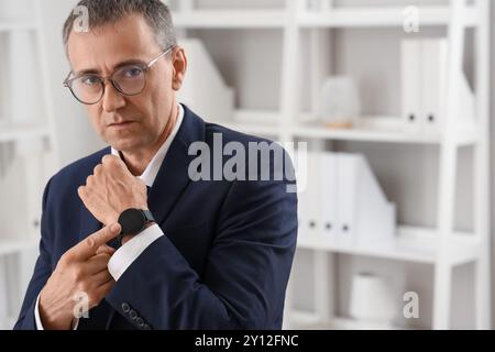 Mature businessman pointing at smartwatch in office. Banner for design ...