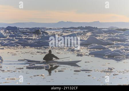 Inuit paddling a kayak between icebergs, man, sunny, summer, Ilulissat ...