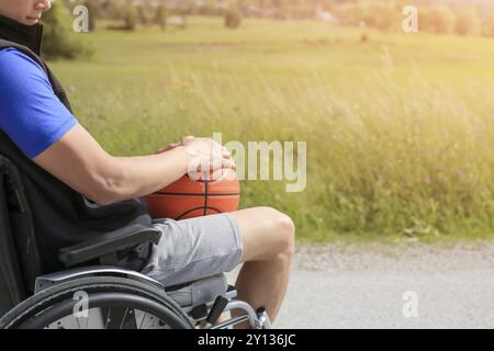 Disabled young basketball player on a wheelchair holding ball and ...