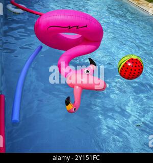 Colorful inflatable flamingos and balls floating in a sunny swimming ...