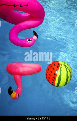 Colorful inflatable flamingos and balls floating in a sunny swimming ...