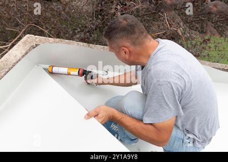 Man using sealant gun at roofing construction. Construction worker with ...