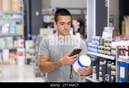 Man scanning barcode on paint can with smartphone in hardware store ...
