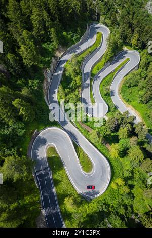 Aerial view of a winding road snakes through the dark, forested terrain ...