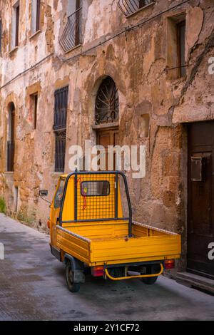 Iconic yellow Piaggio Ape three wheeler on an antique street of Italy ...