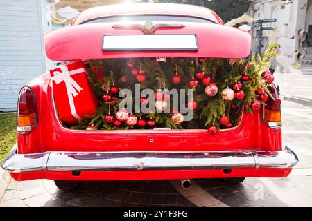 An opened red car trunk filled with cloth bags full of gifts and ...