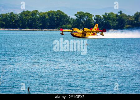 A yellow firefighting plane skims the surface of Lake Kerkini in Greece ...