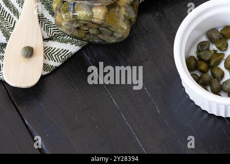 Image composed of a caper on top of a spoon and part of a jar of ...