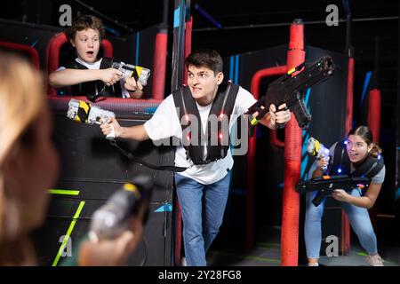 Two guys and one girl running and dodging while playing lasertag Stock ...