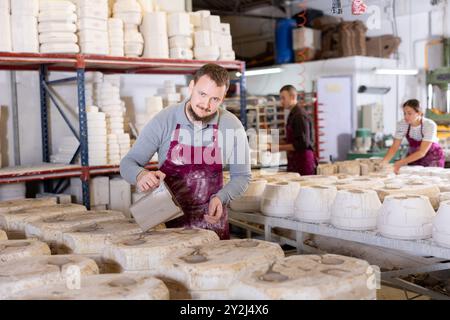 Young man pouring clay into mold Stock Photo - Alamy