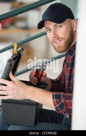 Handsome man with beard by construction stairs wearing hardhat afraid ...