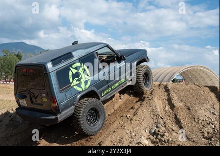 Rear view of a modified green Land Rover Defender pickup climbing a ...