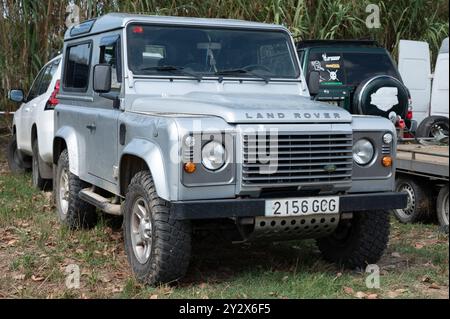 Modified silver Land Rover Defender 110 LWB climbing a steep dirt hill ...