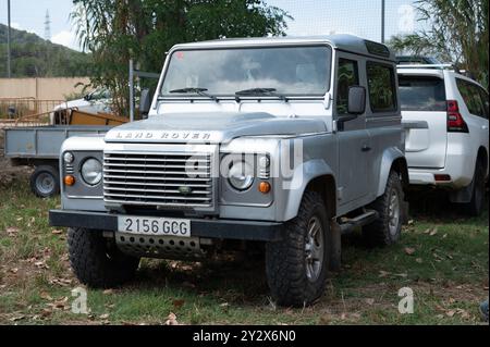 Modified silver Land Rover Defender 110 LWB climbing a steep dirt hill ...