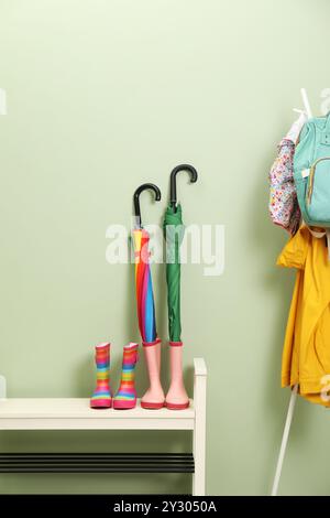 Interior of hallway with rubber boots and umbrellas near light wall ...