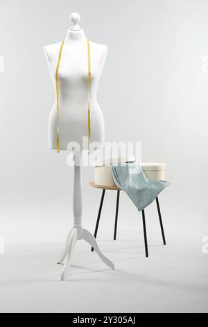 Mannequin with fabric and boxes on side tables against light grey ...