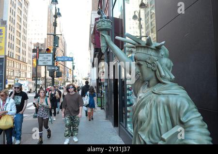 People walk past a model of the Statue of Liberty outside of a store in ...