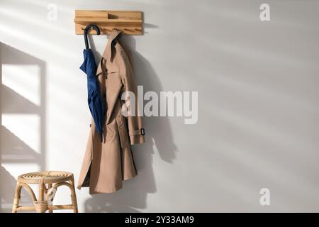 Colorful umbrella and trench coat hanging on rack at home Stock Photo ...