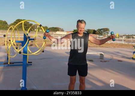 A hispanic older man doing external shoulder rotation exercise with ...