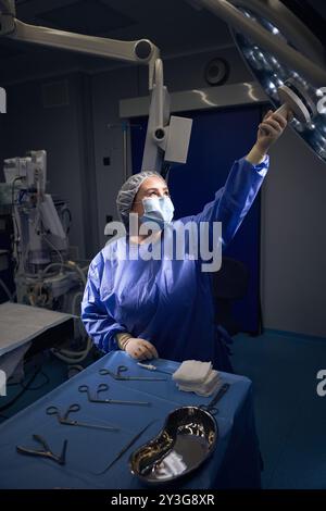 Female assistant reaches to adjust an overhead surgical light Stock ...