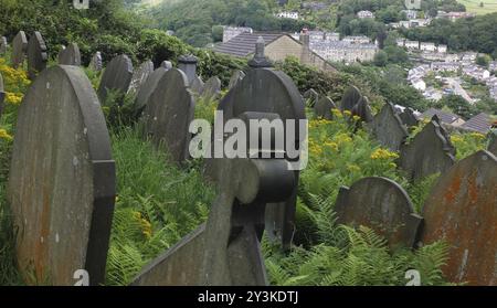 Gravestones overgrown with weeds overlooking the town of hebden bridge ...