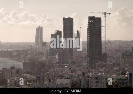 Construction cranes towering over Limassol city skyline with hazy sky ...