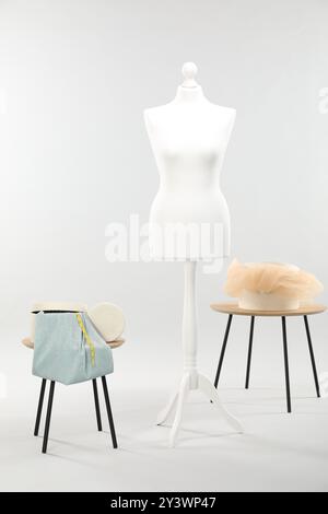 Mannequin with fabric and boxes on side tables against light grey ...