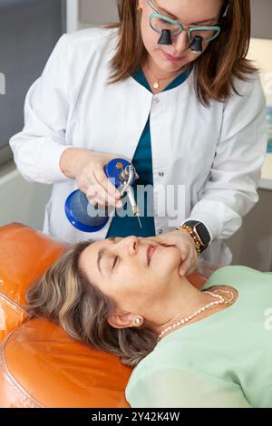 Dermatologist applying cryotherapy for skin lesions on a senior female ...