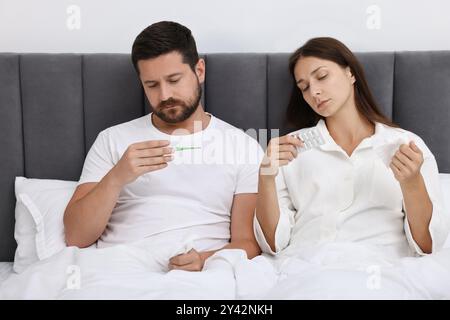 Cold symptom. Couple suffering from fever on bed at home Stock Photo ...