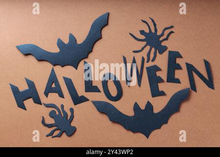 Black Paper Cutouts of Bats, Spiders and Word Halloween on Brown ...
