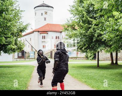 Two fencers dressed in black protective uniforms, helmets with face ...