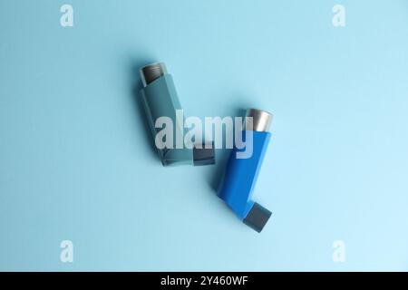 Asthma inhalers on light blue background, top view. Space for text ...