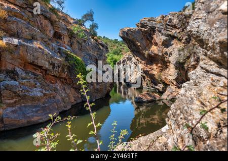 Narrow rocky gorge with still green water at Pego das Pias, a hidden ...