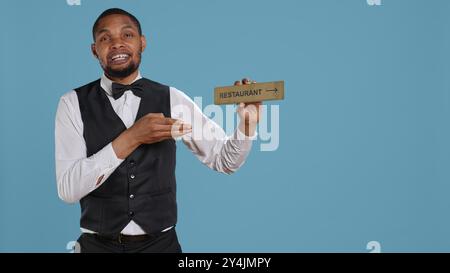 Doorman bellhop showing the restaurant direction with a hotel sign ...