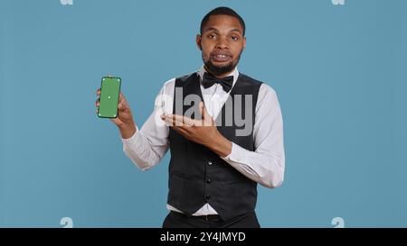 Hotel worker bellhop points at phone with isolated mockup display ...