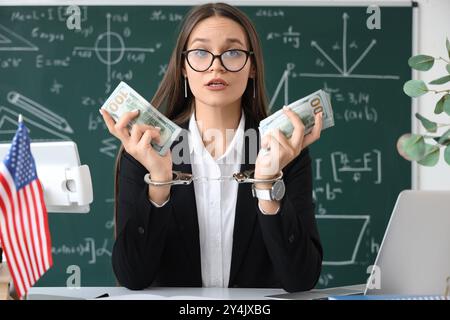 Handcuffed female teacher with bribe in classroom. Corruption concept ...