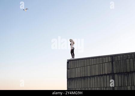 Side view of unrecognizable female in dress standing on couch against ...
