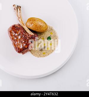 Elegant plating of a juicy lamb chop with golden roasted potatoes on a ...