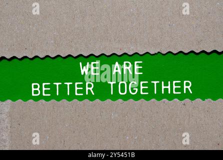 We are better together message written on ripped torn orange paper on black background ...
