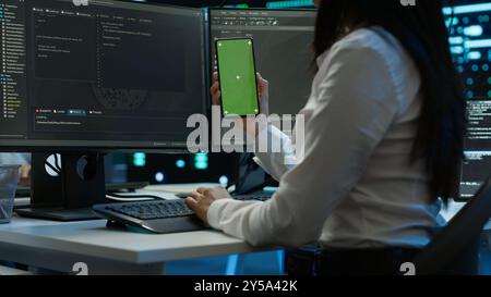 Worker overseeing data center using green screen mobile phone, ensuring ...