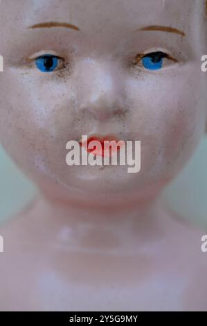 Detail of face of 1950s girl doll with bright blue eyes red lips and ...