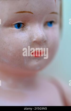 Detail of face of 1950s girl doll with bright blue eyes red lips and ...