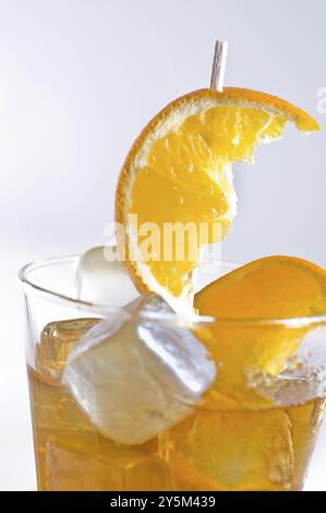 Orange colored iced-tea with ice-cubes against bright white background ...