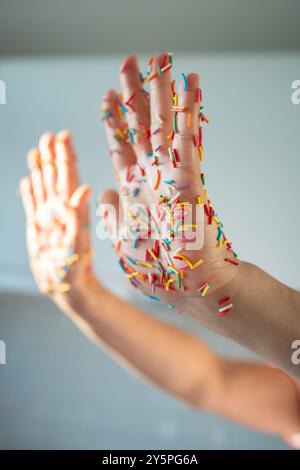 Sticky hands with colorful sprinkles for decorating cupcakes, doughnuts ...