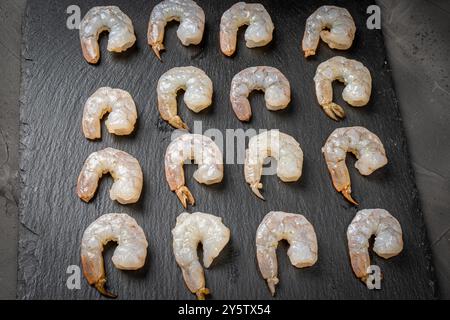 Rows of fresh raw prawn and shrimp arranged on metal tray with herbs ...